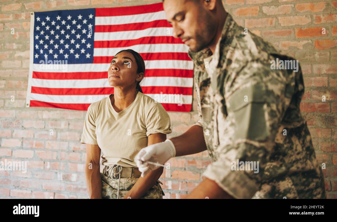 Young male nurse preparing to vaccinate a servicewoman in the army ...