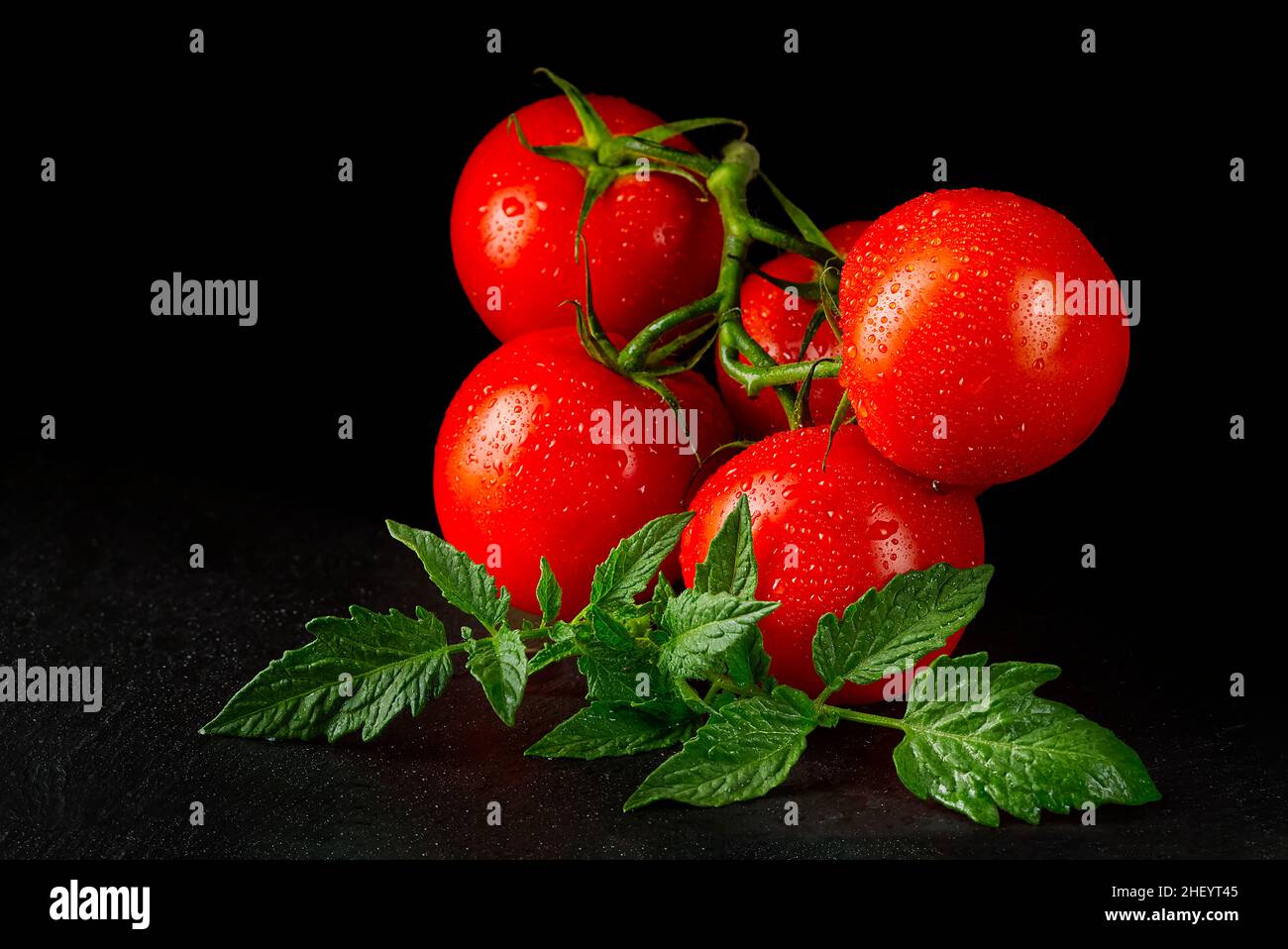 Ripe organic tomatoes on the black table in low key with water drops Stock Photo - Alamy
