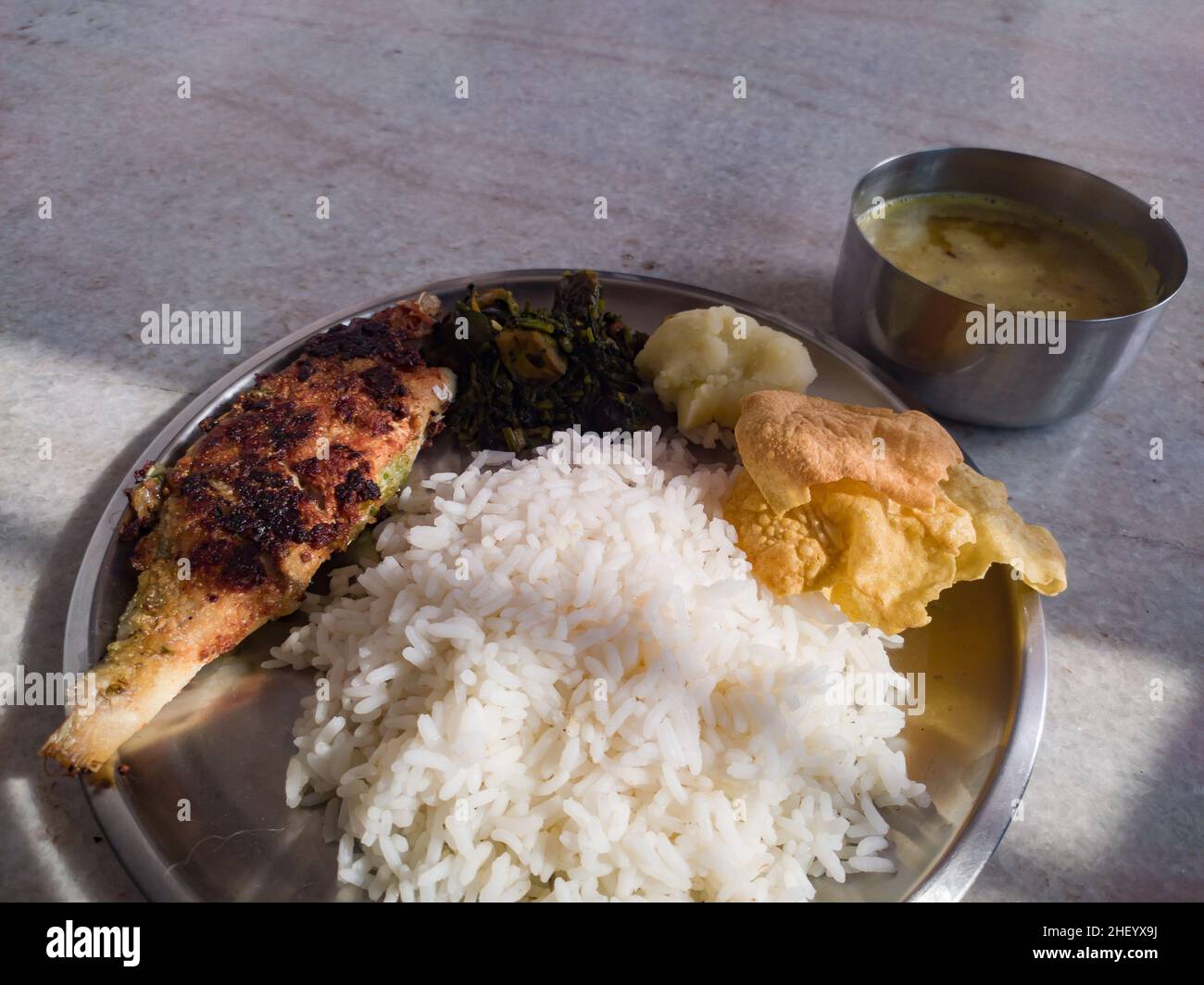 bengali staple food of rice and fish served in a plate with other side ...