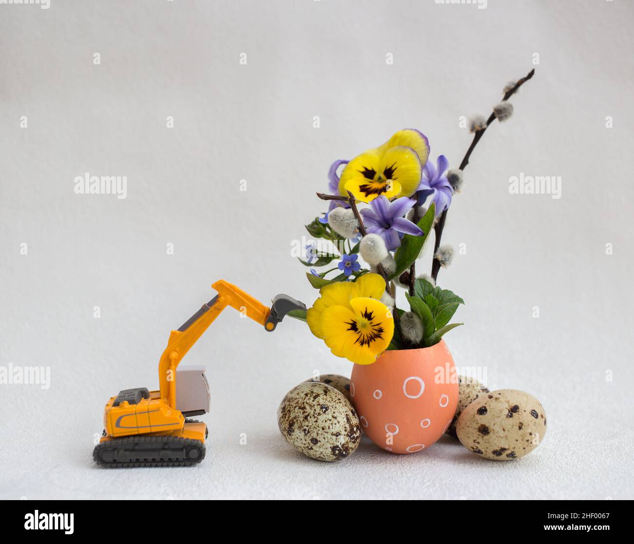 model of toy excavator with Easter composition of spring flowers and ...