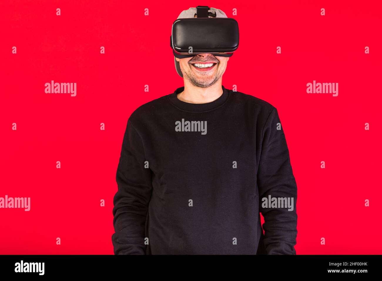 Man in cap dressed in black wearing Virtual Reality glasses, smiling ...