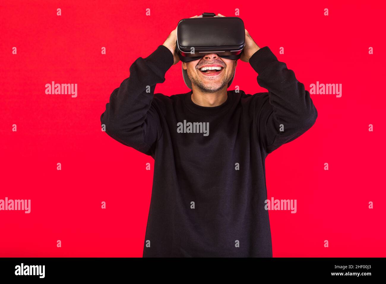 Man in cap dressed in black wearing Virtual Reality glasses, smiling ...