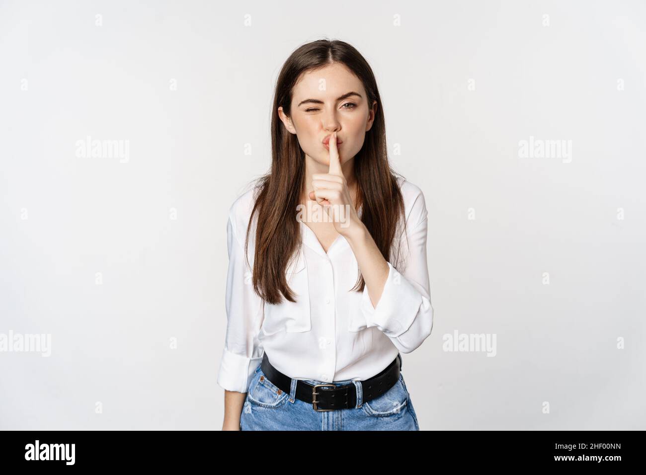 Smiling beautiful woman shushing, making hush shh sign, press finger to ...