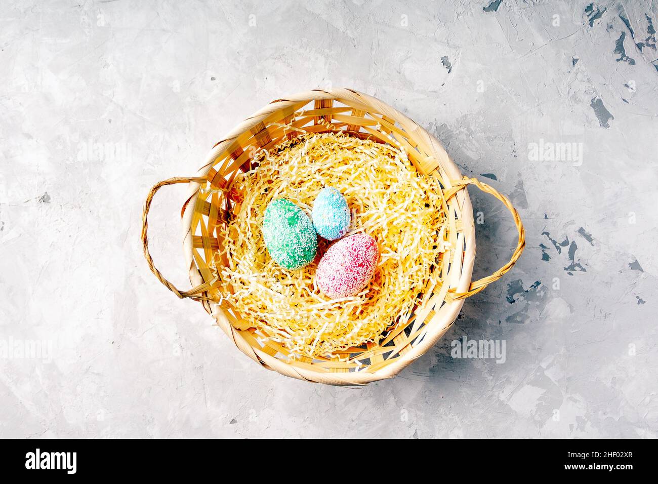Pink green blue pastel eggs in basket on grey background with space for ...