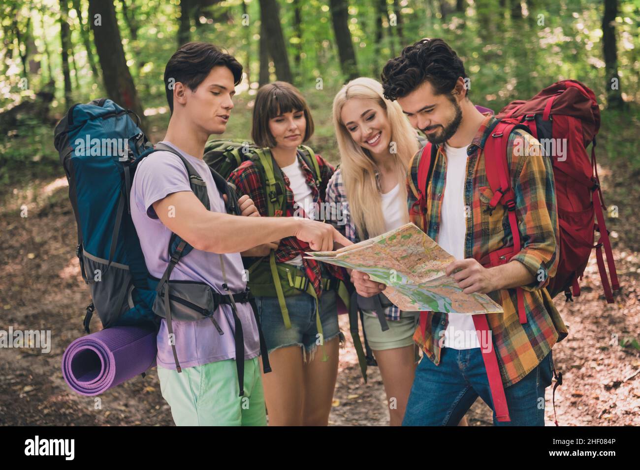 Portrait of attractive cheerful group of four people exploring wild ...