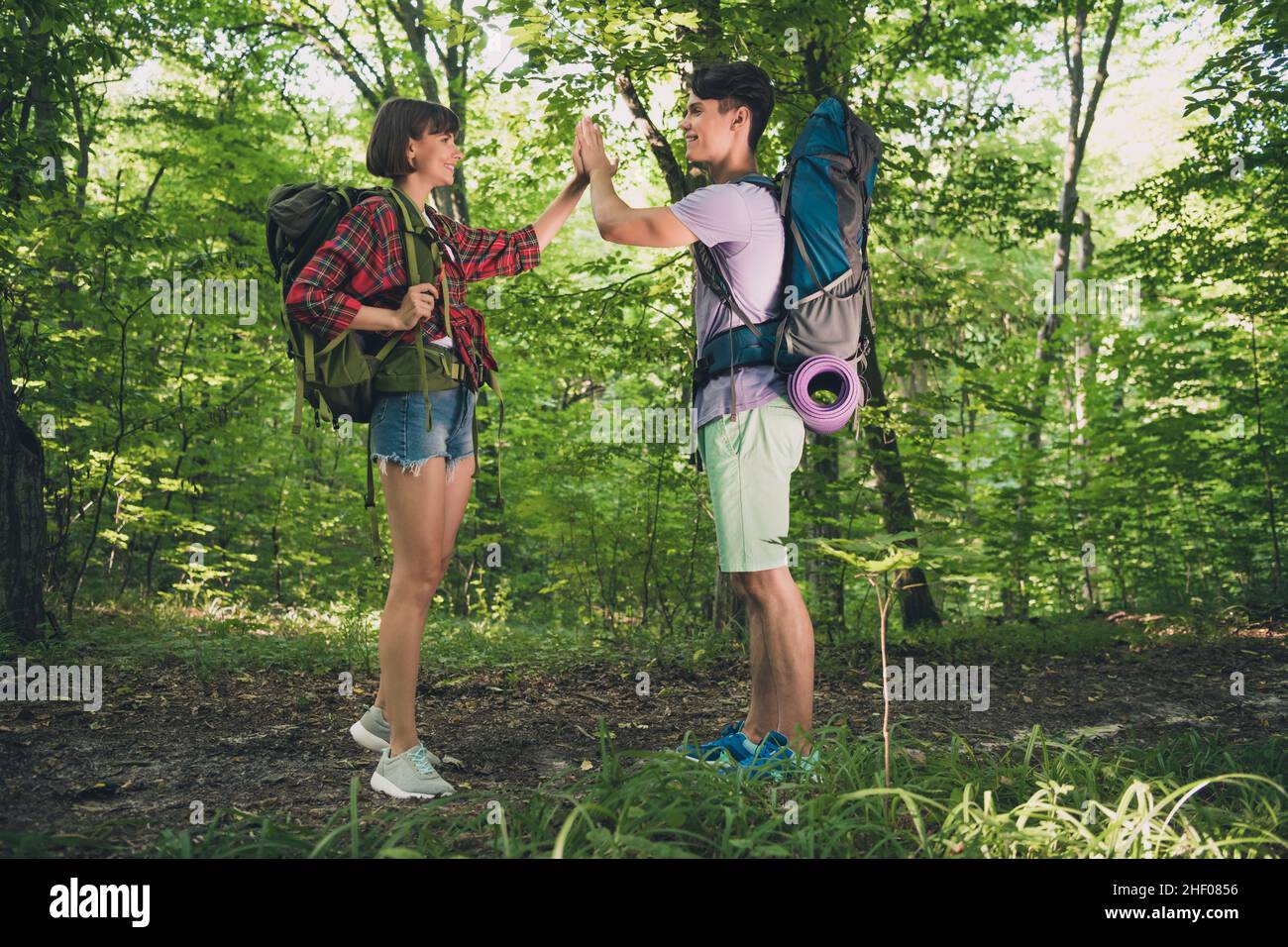 Portrait of attractive cheerful two people exploring wild wood clapping ...