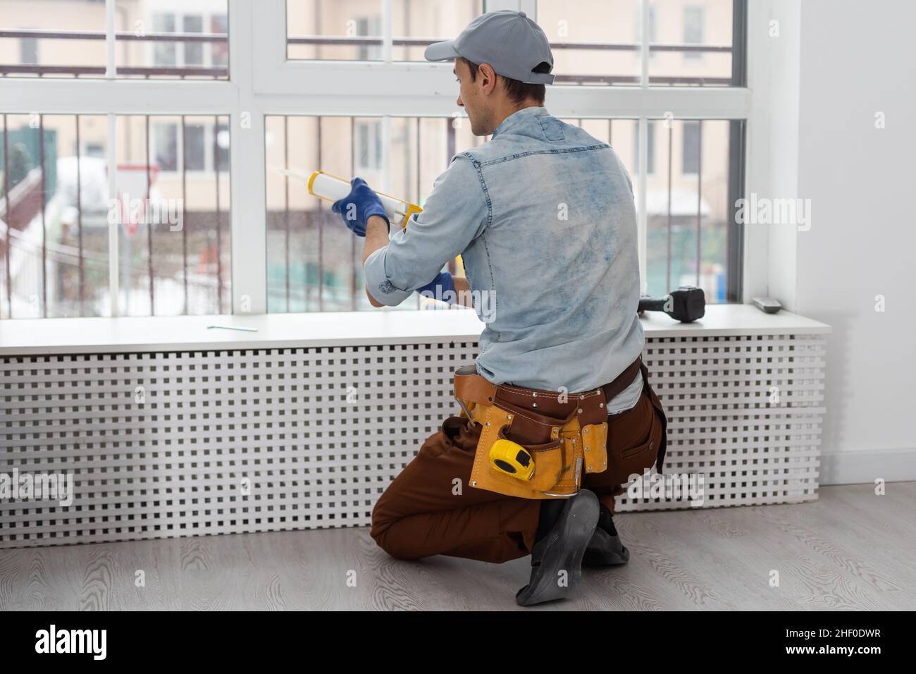 handsome young man installing bay window in a new house construction ...