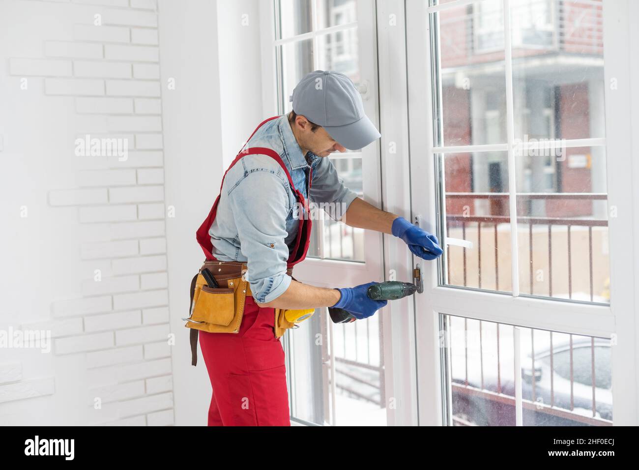 Man fixing lock to window with electric screwdriver Stock Photo - Alamy