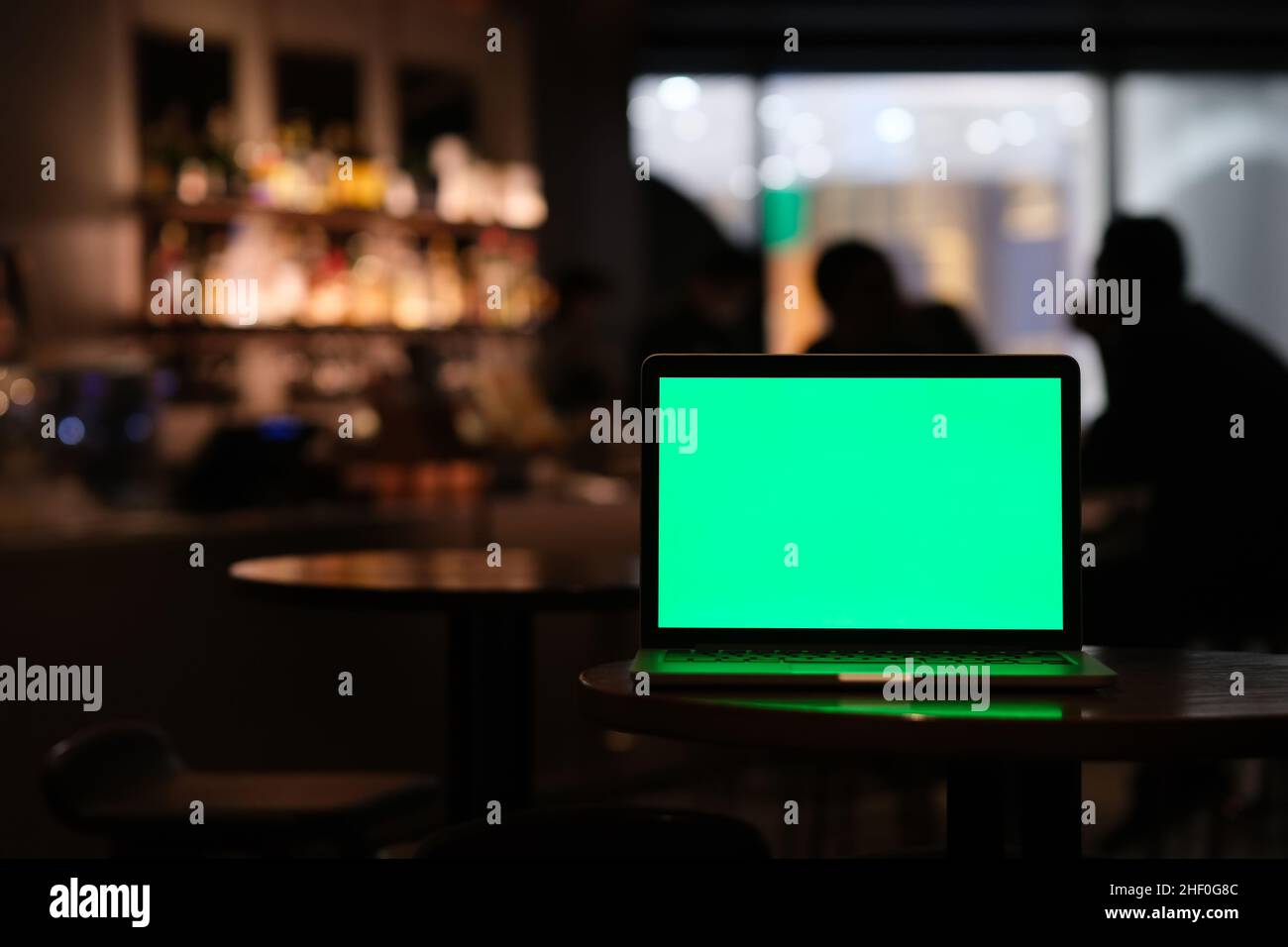 green screen laptop computer on bar table at night Stock Photo - Alamy