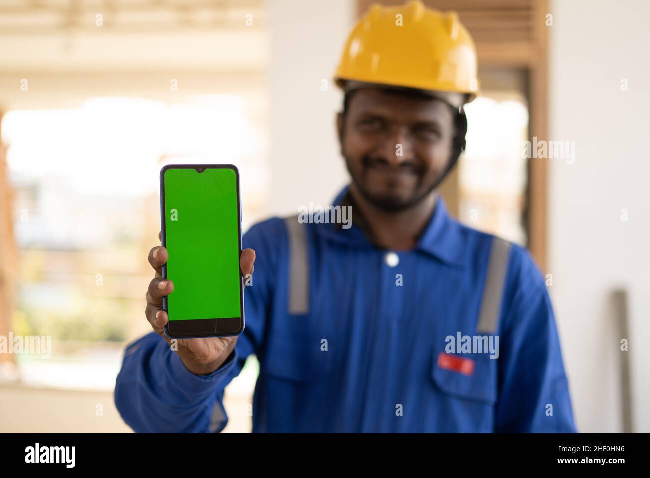 Focus on mobile pone, smiling plumber showing mobile phone with green ...