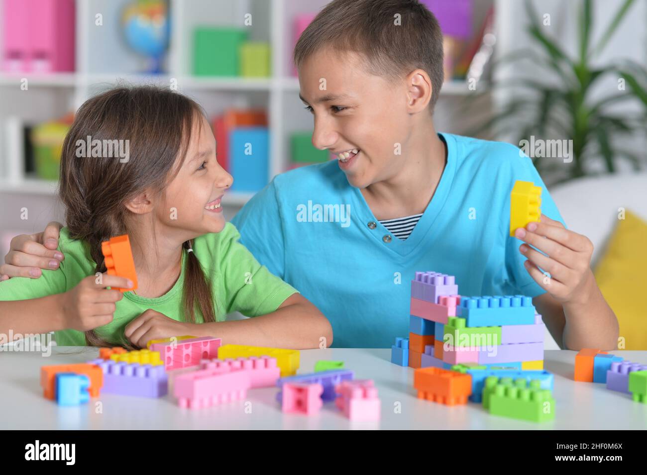 Brother and sister playing with colorful plastic blocks together Stock ...