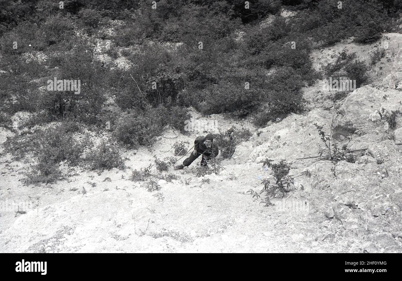 1960s, historical, a view from above of a male rock climber lowering ...