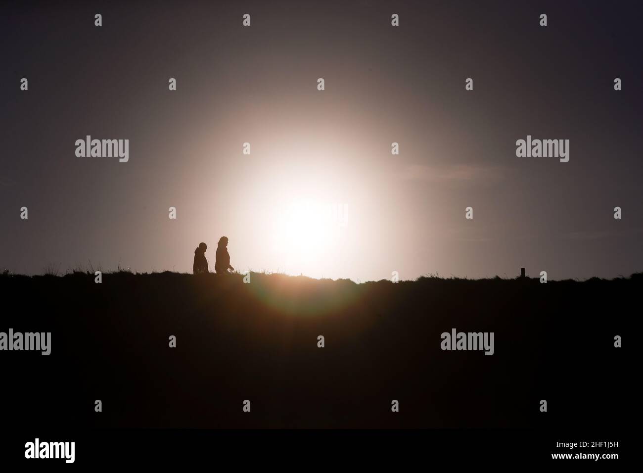 People walk in the winter sun along the beach at Ballycastle, Co ...