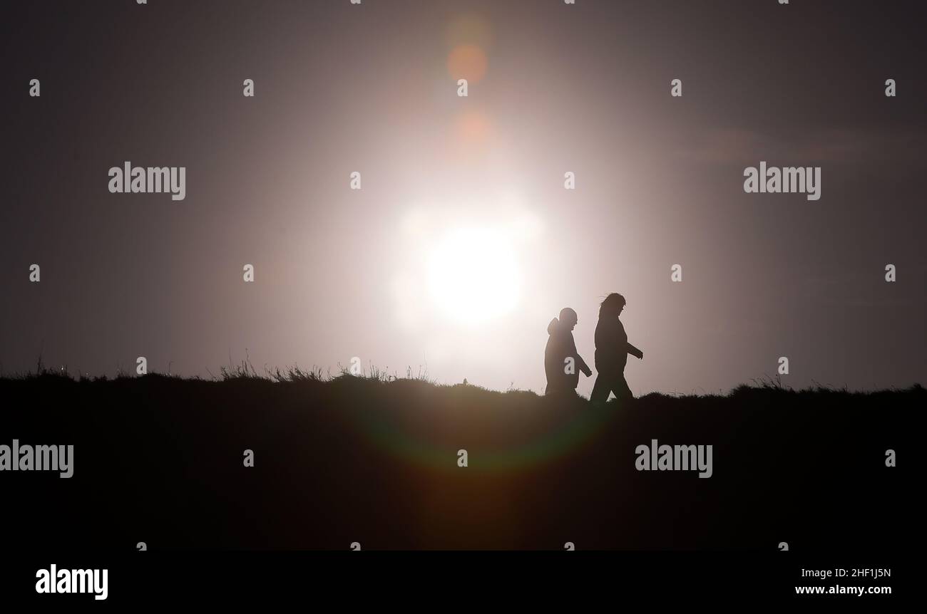 People walk in the winter sun along the beach at Ballycastle, Co ...
