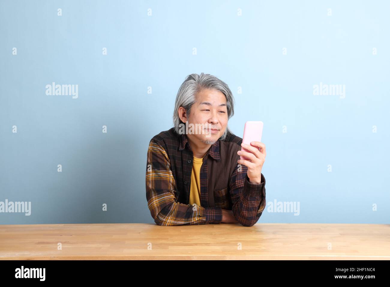The senior Asian man using smart phone at the working desk with blue ...