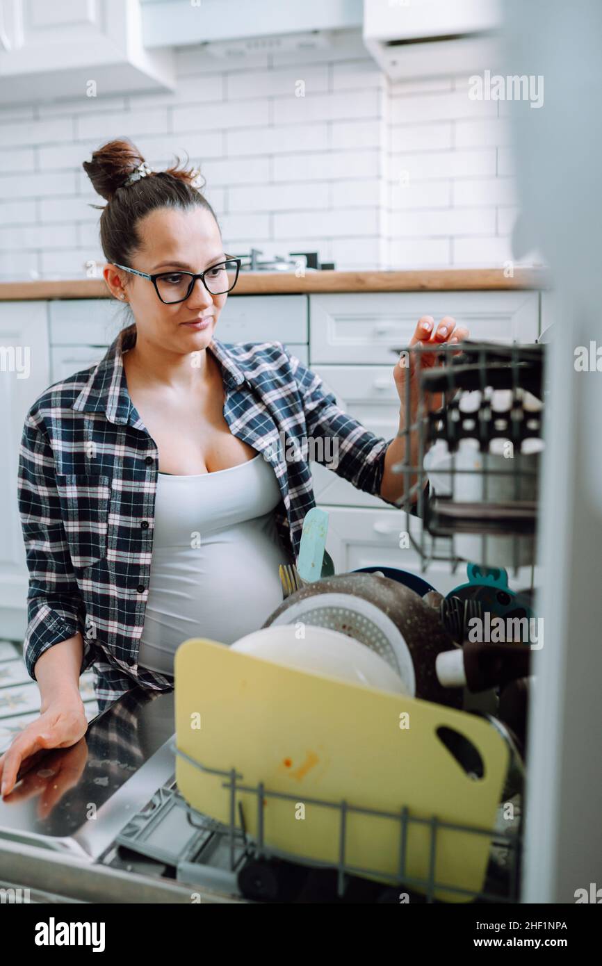 housewife woman load dishwasher making routine work at home in kitchen ...