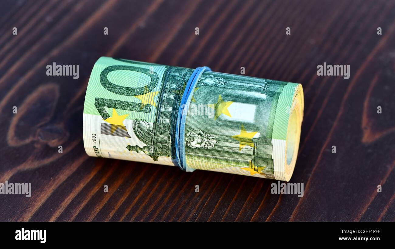 Roll of 5000 Euro in 100 Euro banknotes isolated on wood background ...