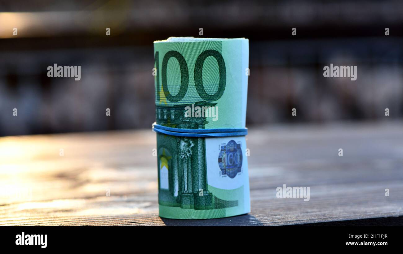 Roll of 5000 Euro in 100 Euro banknotes isolated on wood background ...