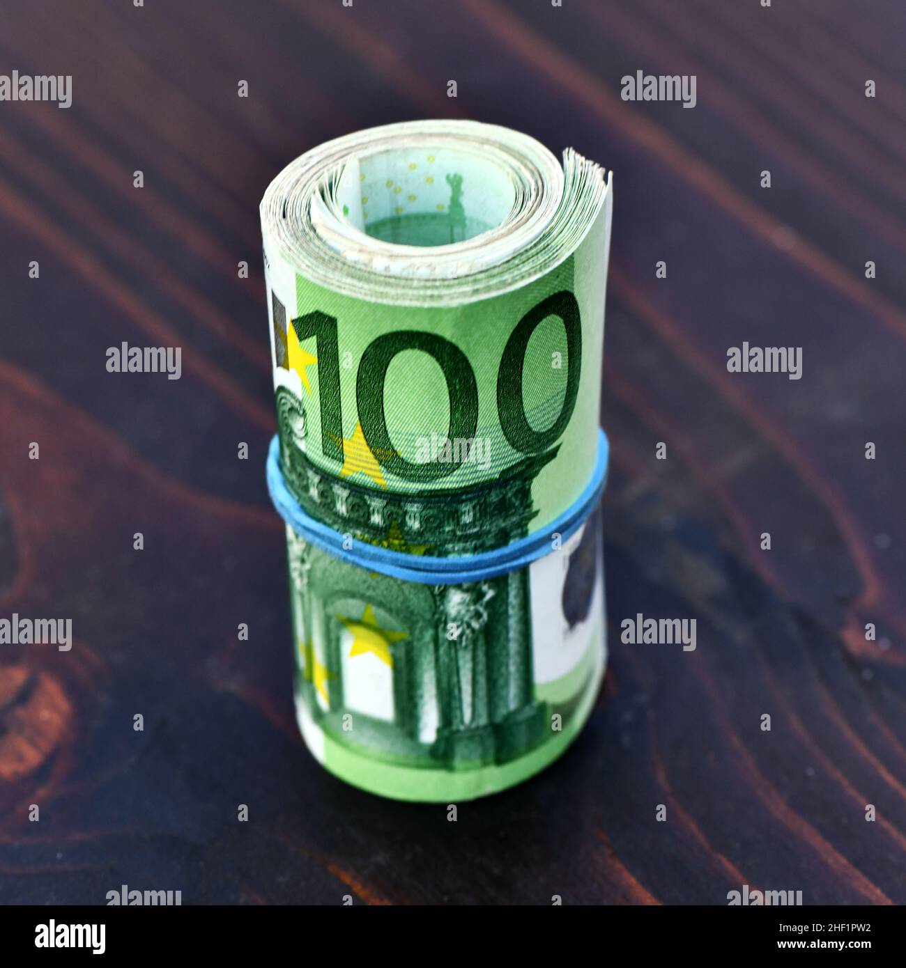 Roll of 5000 Euro in 100 Euro banknotes isolated on wood background ...
