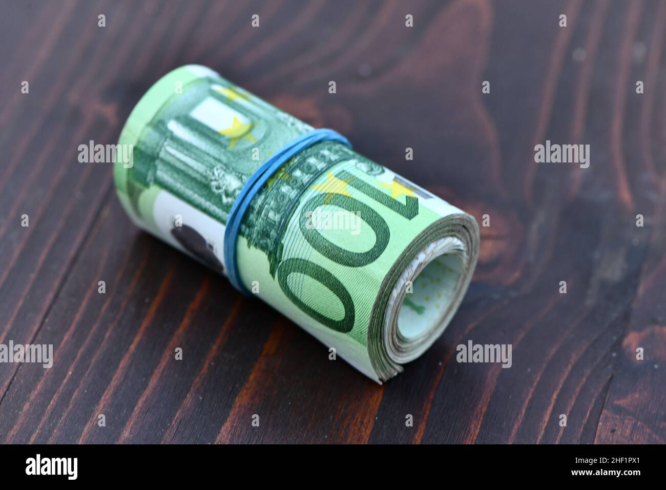 Roll of 5000 Euro in 100 Euro banknotes isolated on wood background ...