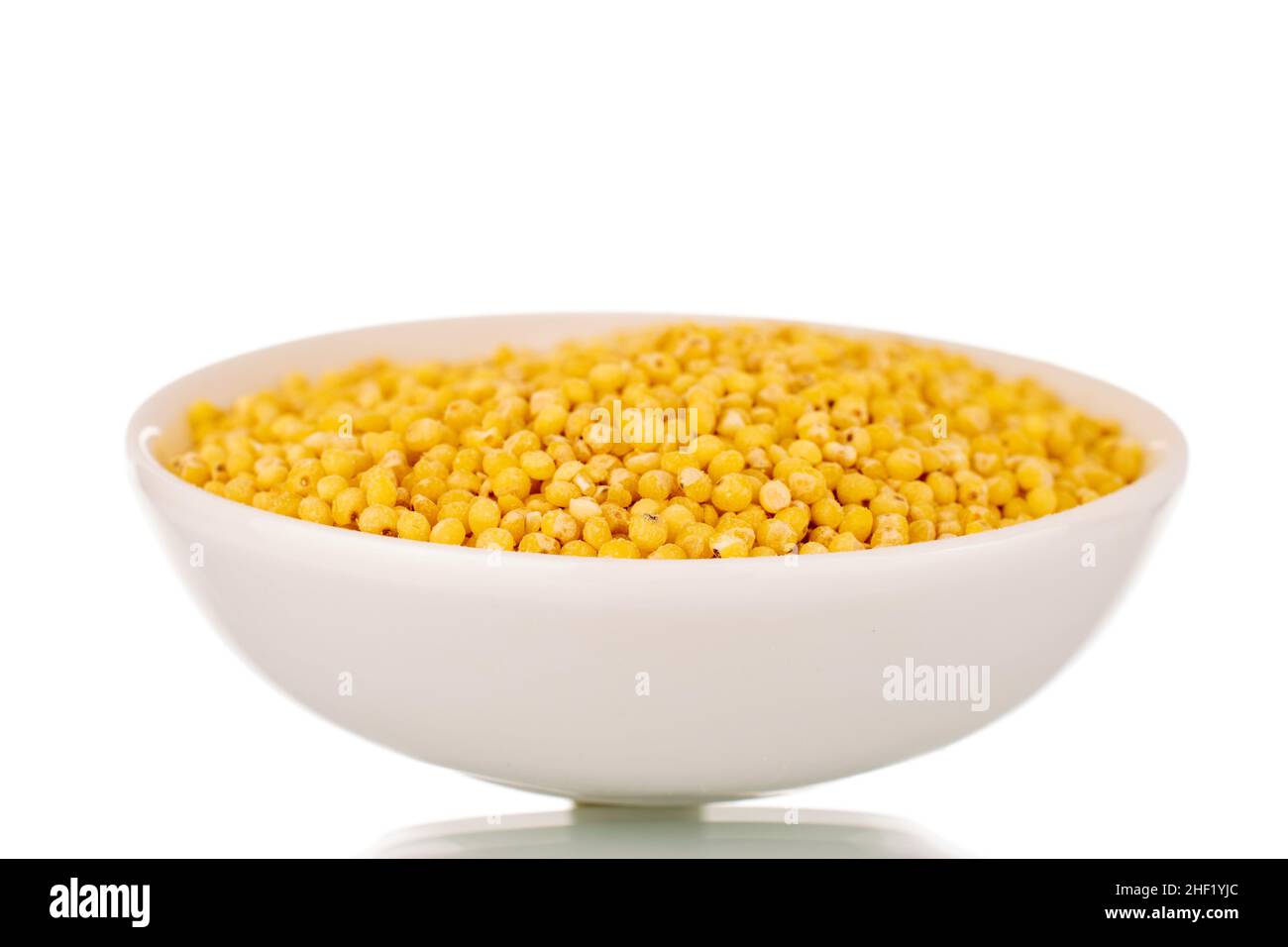 Uncooked organic millet groats in a white ceramic saucer, close-up ...