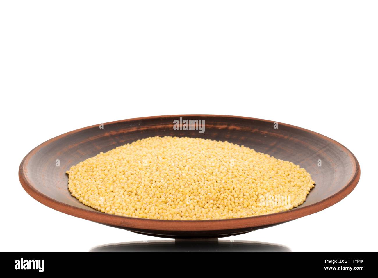 Uncooked organic millet groats on a clay dish, close-up, isolated on ...