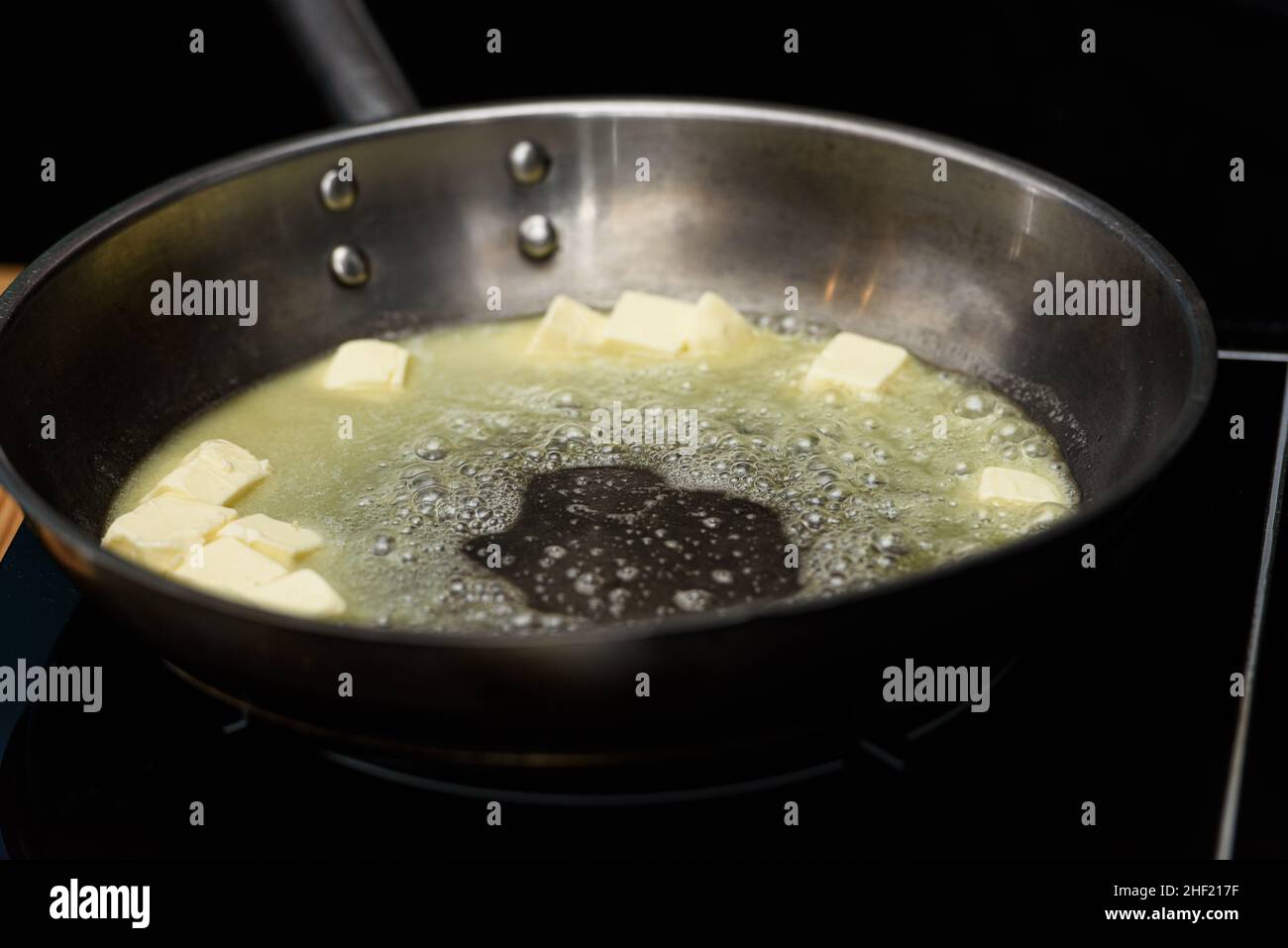 Pieceses of butter melted in a frying pan on a gas stove Stock Photo ...