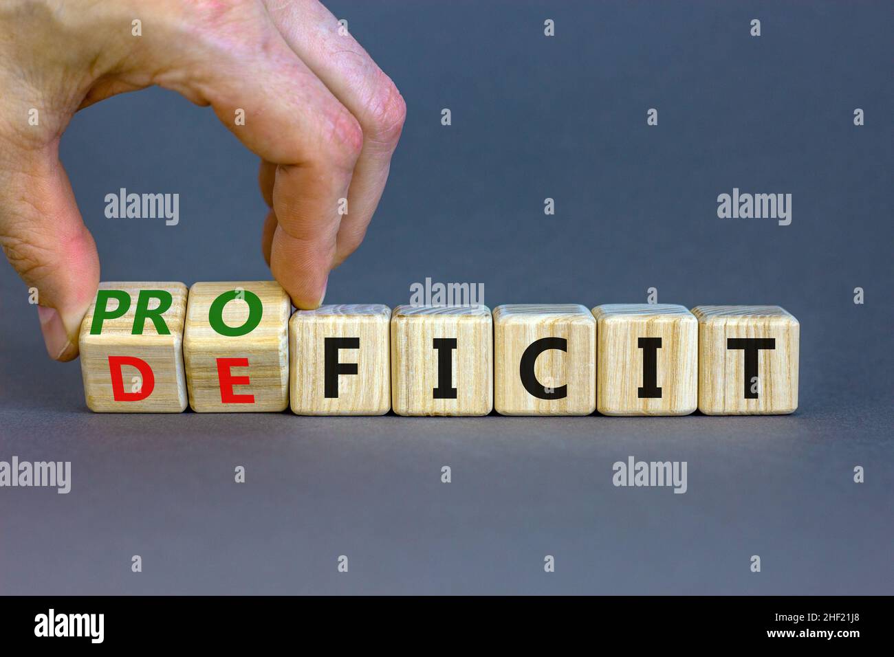 Proficit or deficit symbol. Businessman turns cubes, changes the word deficit to proficit ...