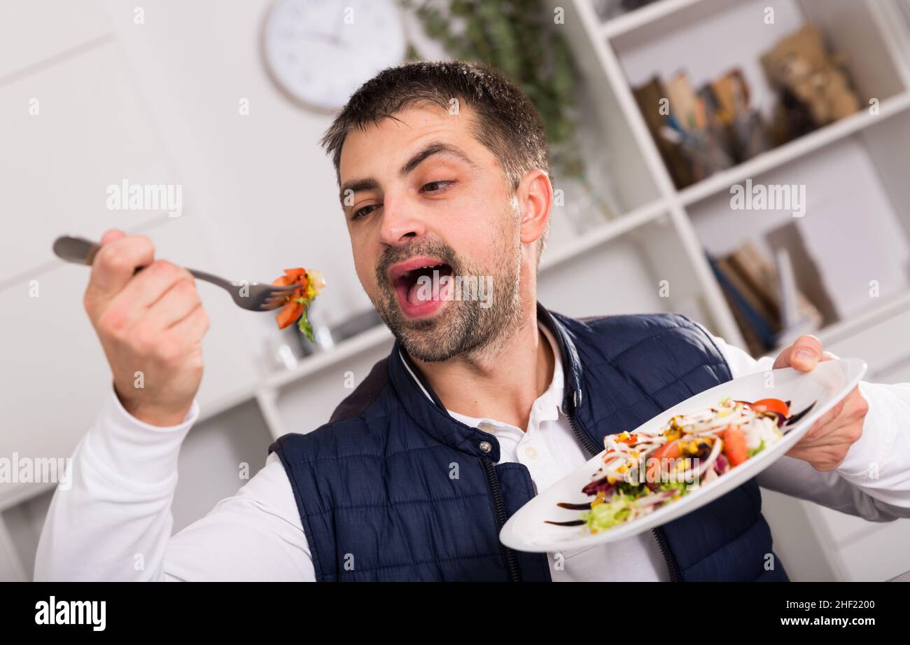 Young man eating vegetable salad from plato Stock Photo - Alamy