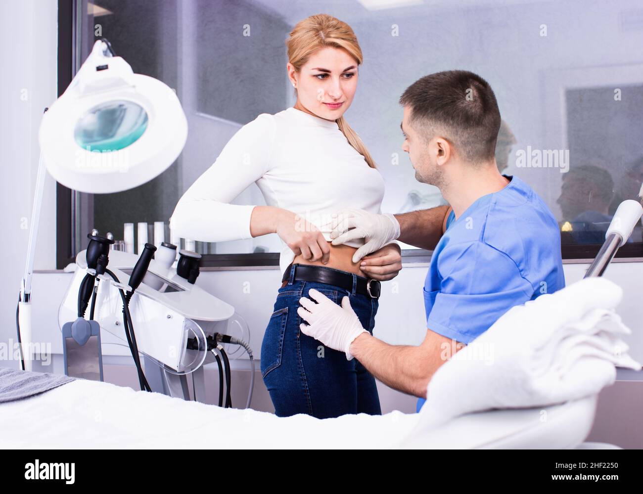 Skilled beautician examining belly skin of young woman Stock Photo - Alamy