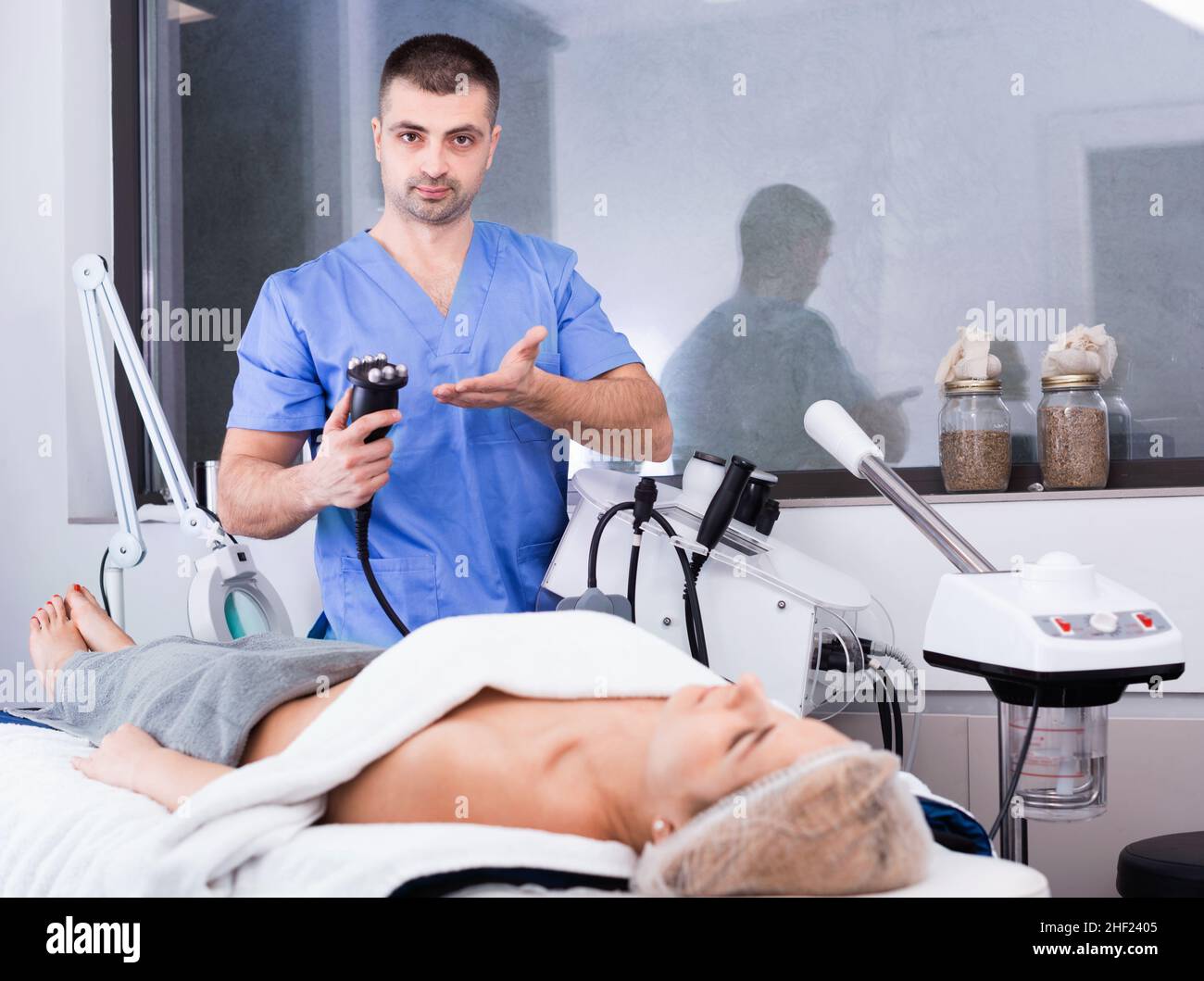 Skilled cosmetologist explaining cosmetic procedure using new equipment ...