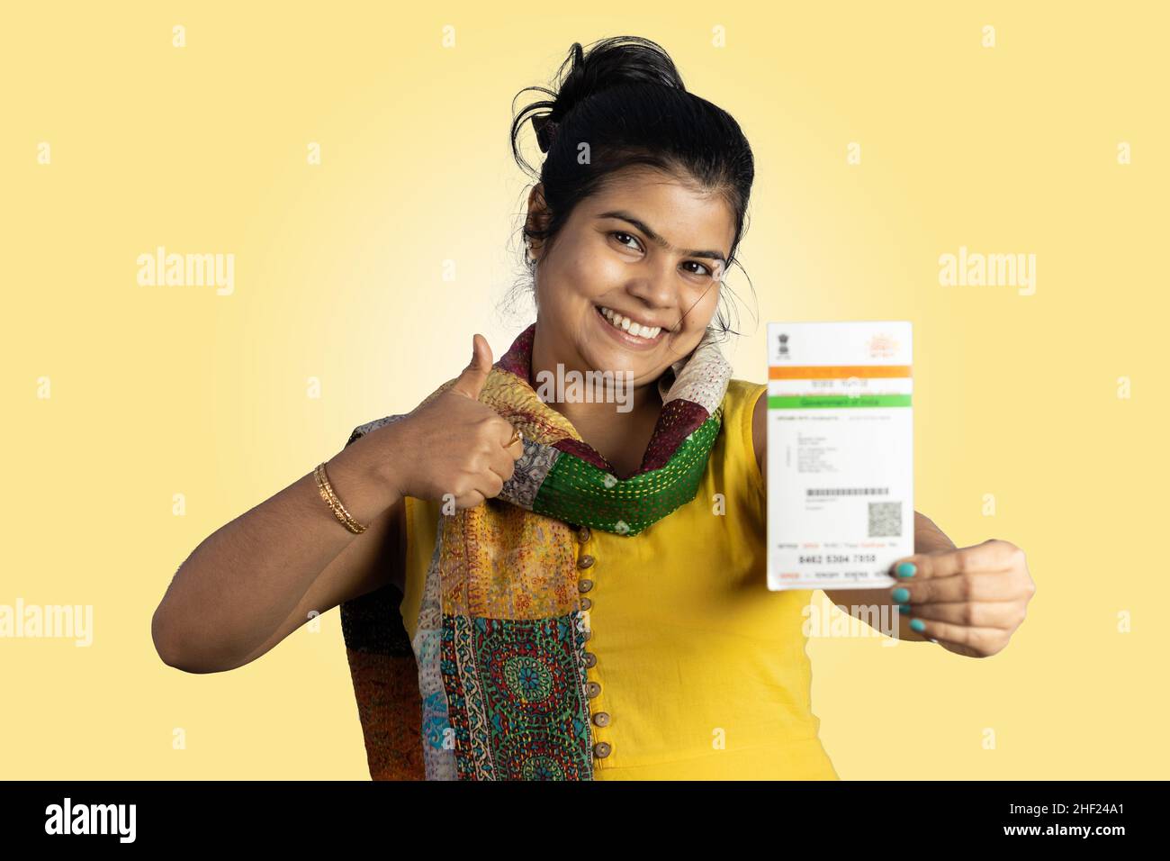 An Indian young woman smiling and pointing to Aadhaar card in hand on ...