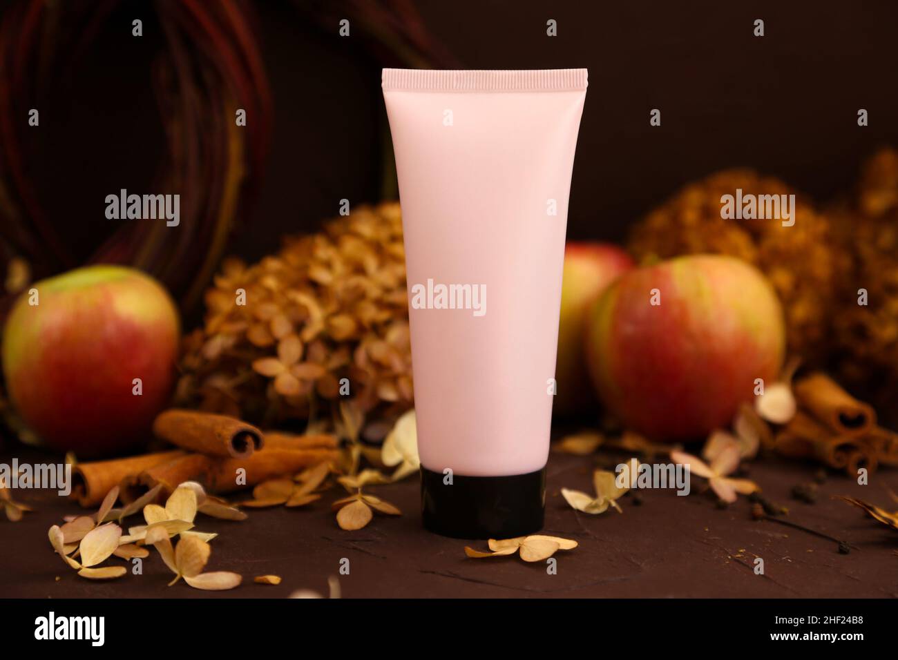 Pink squeeze bottle cosmetic tube with black cap, cinnamon, apples and ...