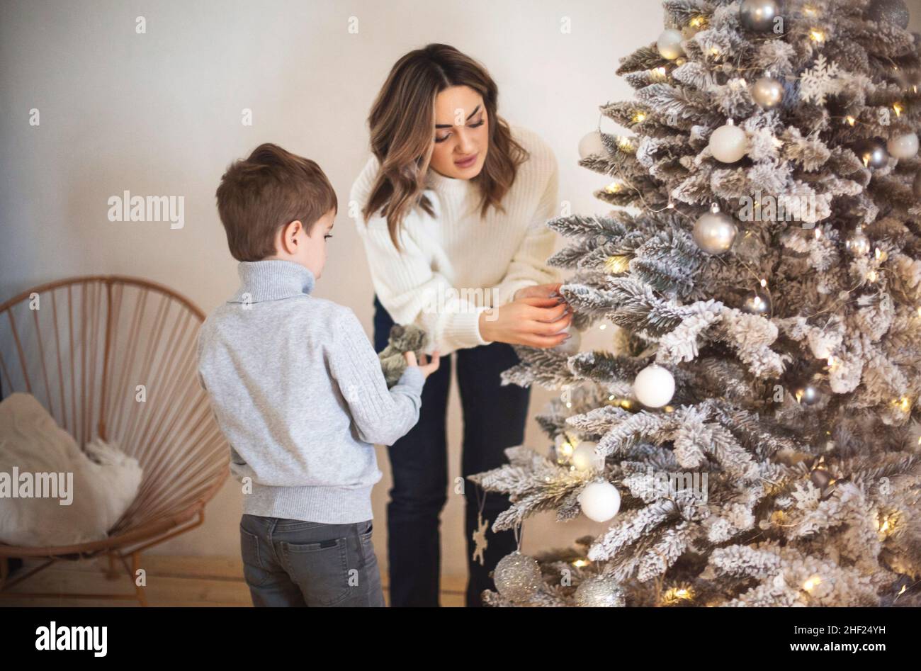 Little preschool boy helping mother to decorate Christmas tree at home ...