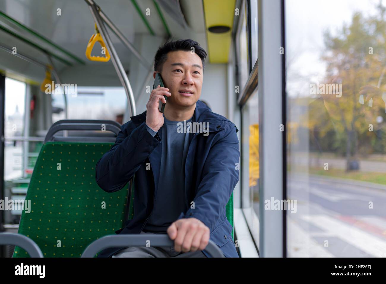 asian man in public bus passenger having fun talking on mobile phone ...