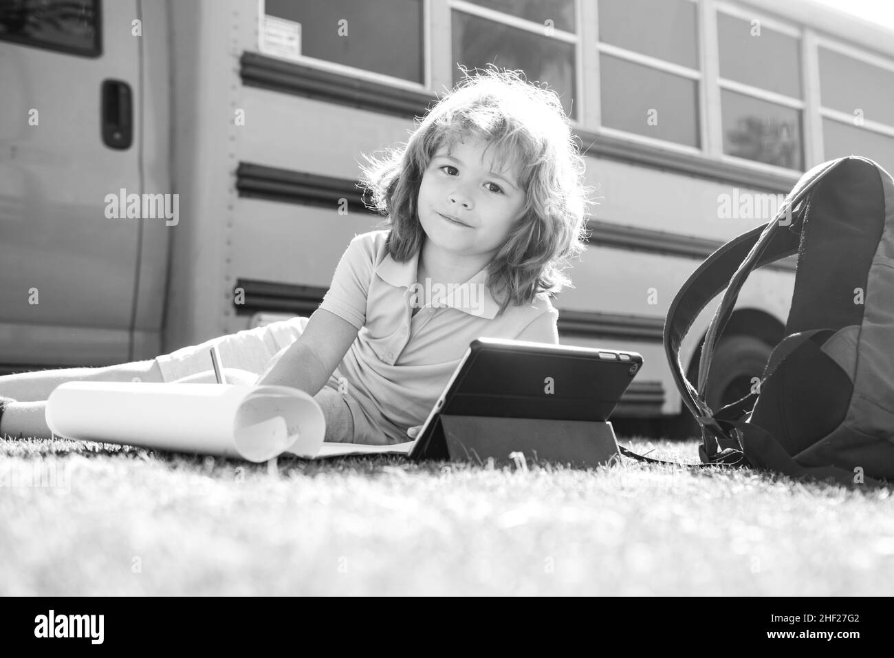 Smart school boy doing homework with digital tablet at school park near ...