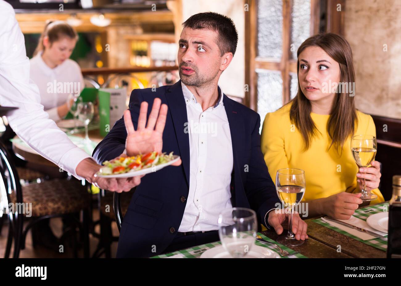 Man is refusing salad in time dining with woman Stock Photo - Alamy