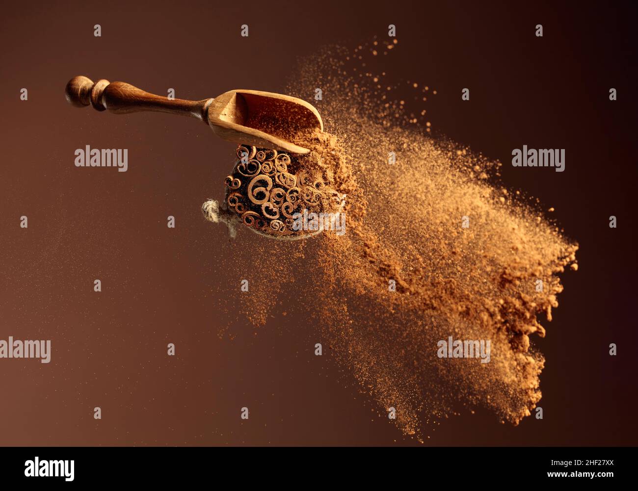 Cinnamon powder is poured out of the wooden spoon. The ground cinnamon ...