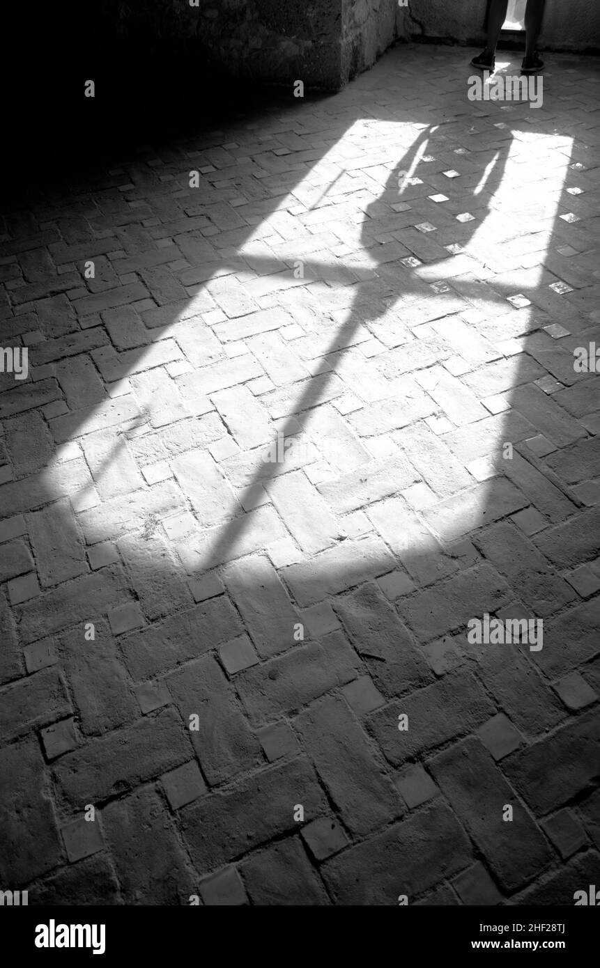 shadow of a man standing in front of a large window in a spacious room ...