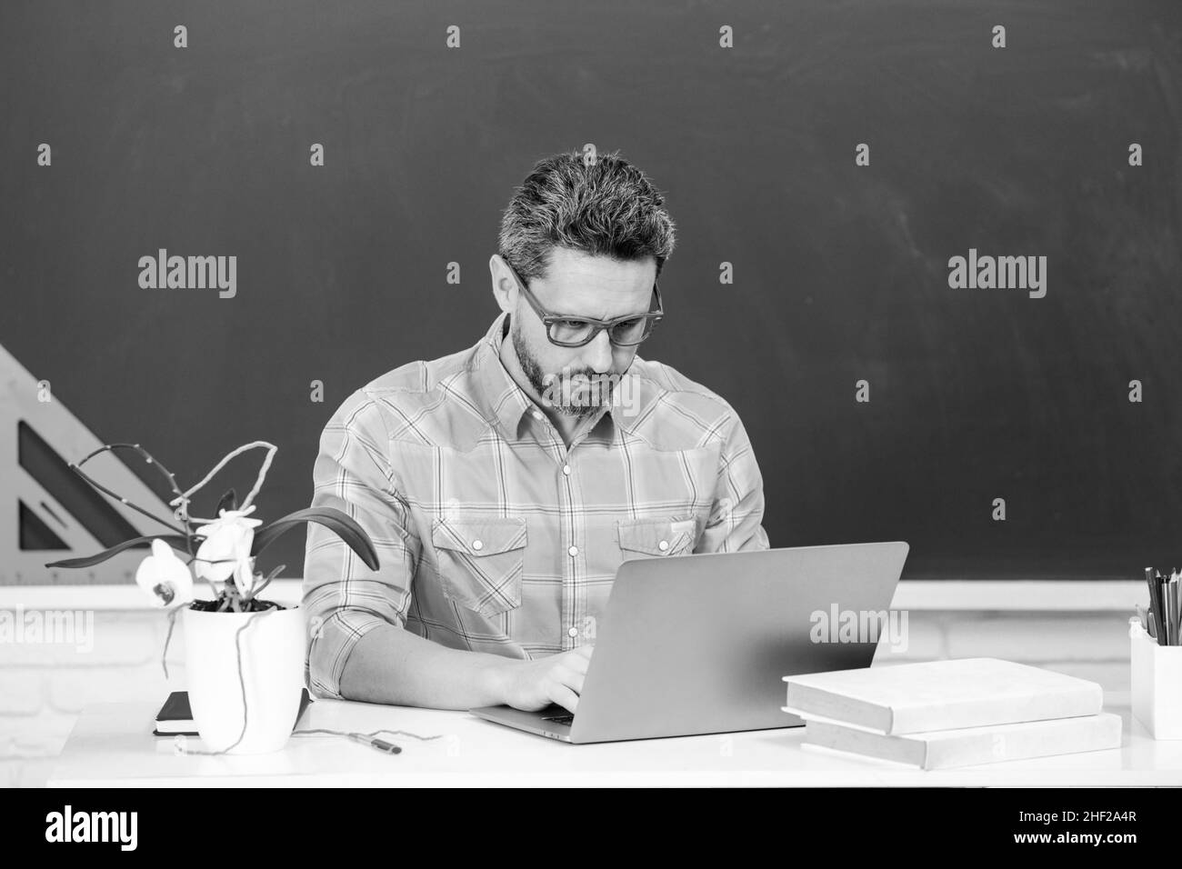 Portrait of confident caucasian male teacher in classroom. Middle aged ...