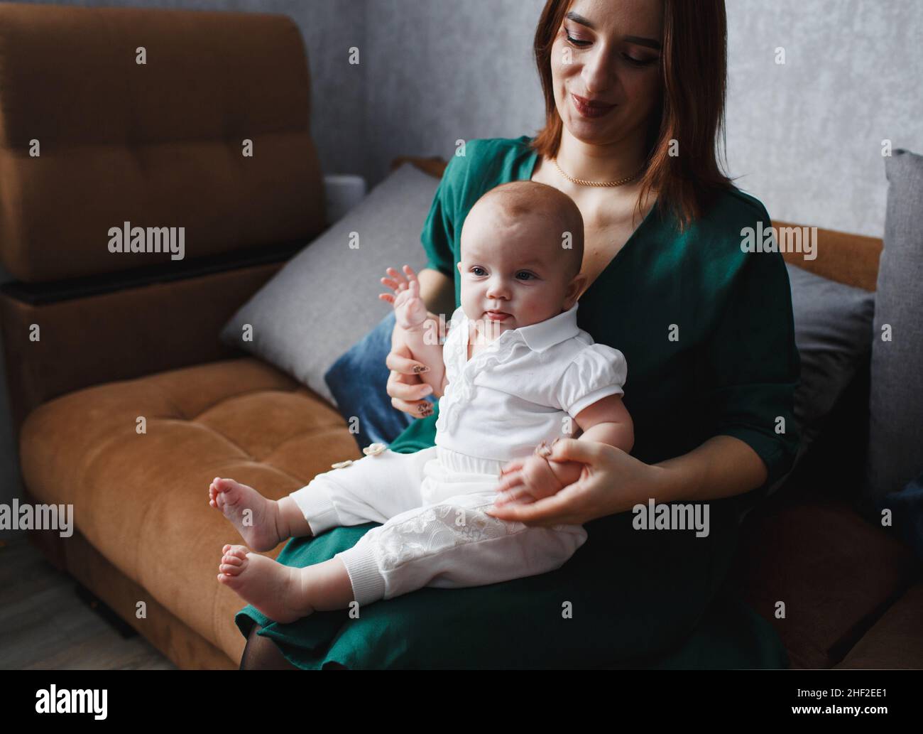 A young tender happy mother hugs her newborn baby, smiling while ...