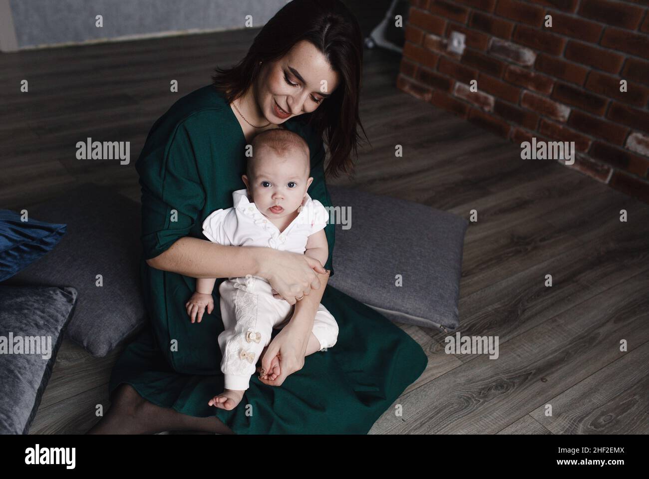 A young tender happy mother hugs her newborn baby, smiling while ...