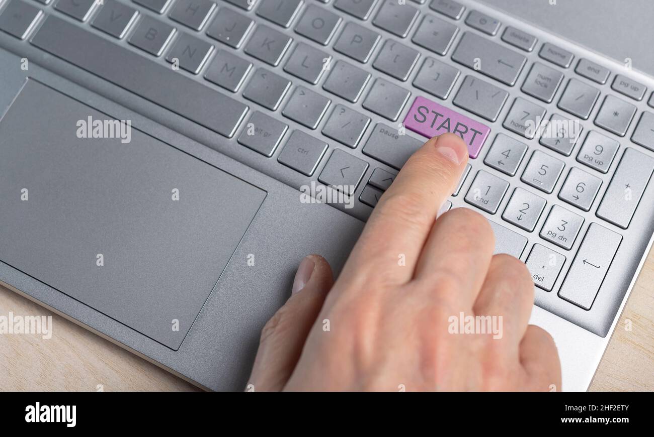 Word start on laptop. Finger pressing launching button on keyboard ...