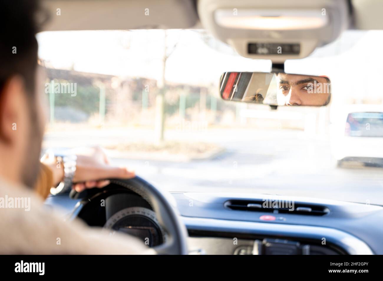 Man holding driving wheel riding car looking in rearview mirror at ...