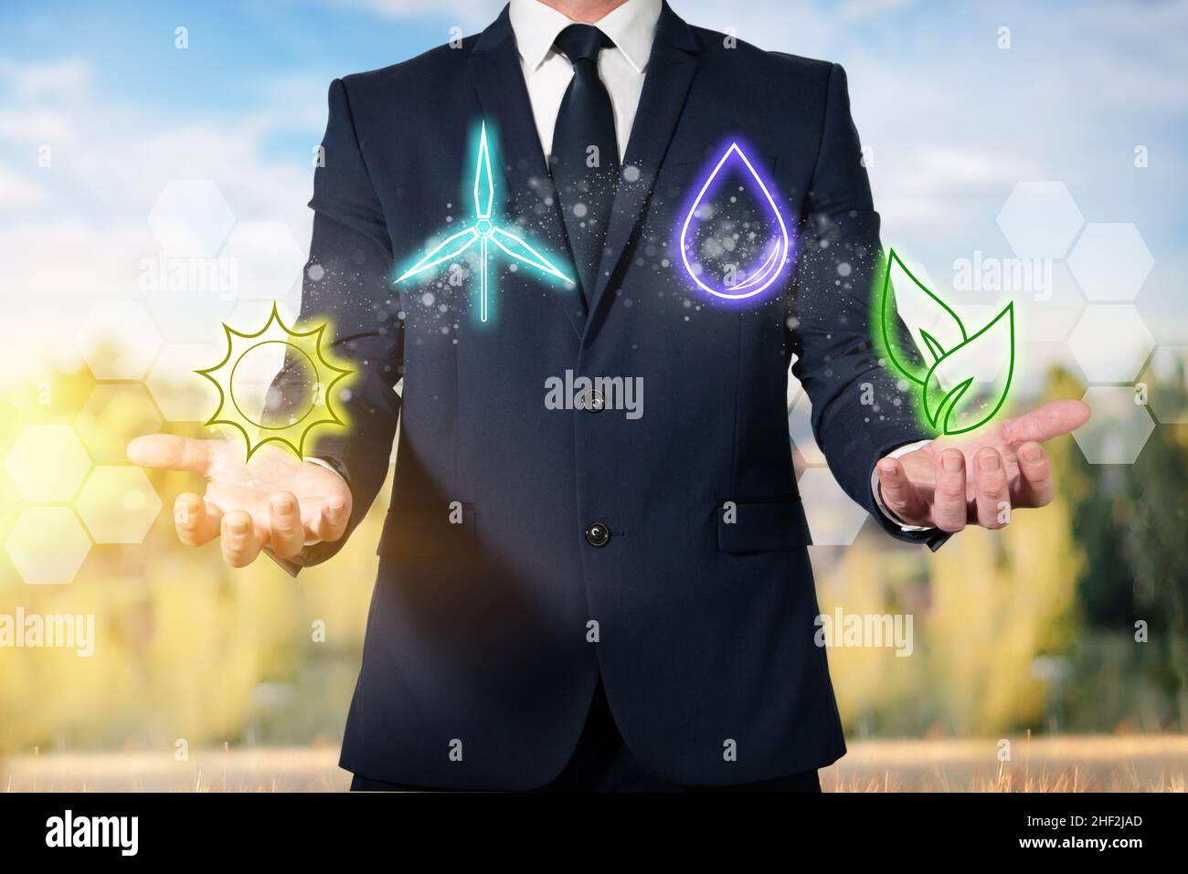 Businessman with open hands holds the symbols of renewable energies ...