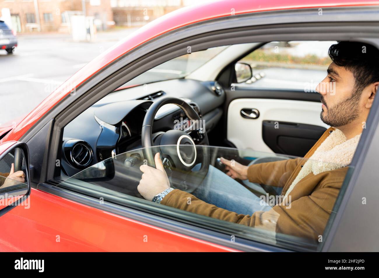 Man in jacket holding driving wheel riding car at daytime. View from ...
