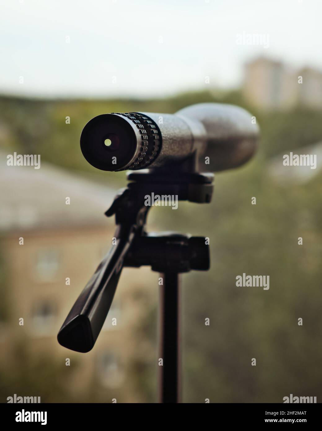 Spyglass or telescope on tripod stands by the window. Surveillance and ...