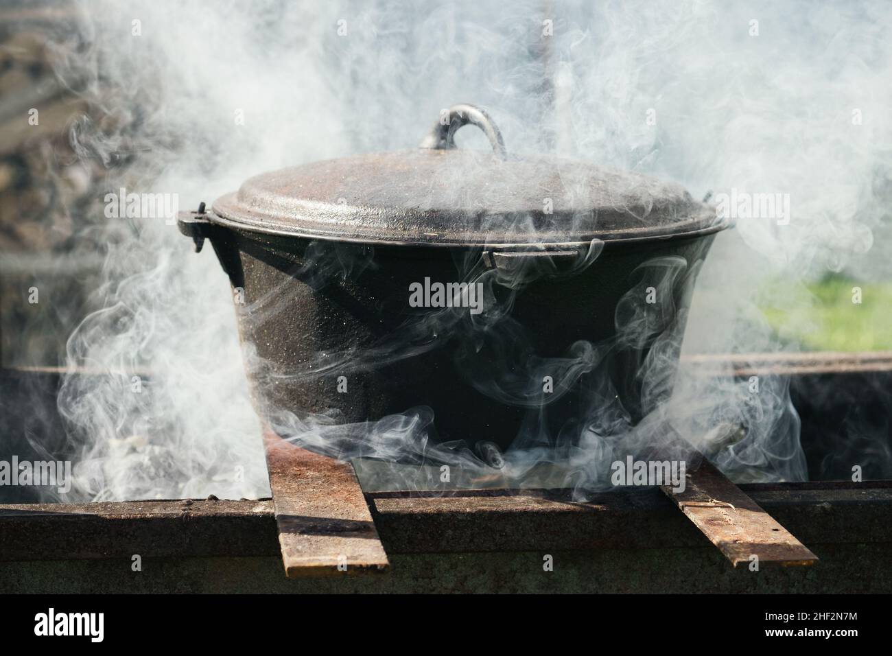 Cauldron over bonfire shrouded in smoke. Cooking food outdoor on fire ...