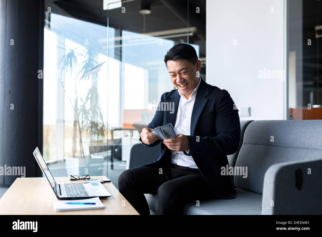 Business owner boss asian, counts cash proceeds sitting in office ...