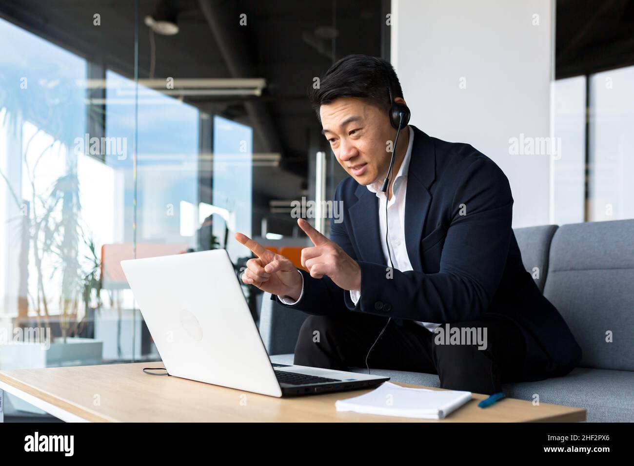 Asian call center employee talking to customers sitting in office ...